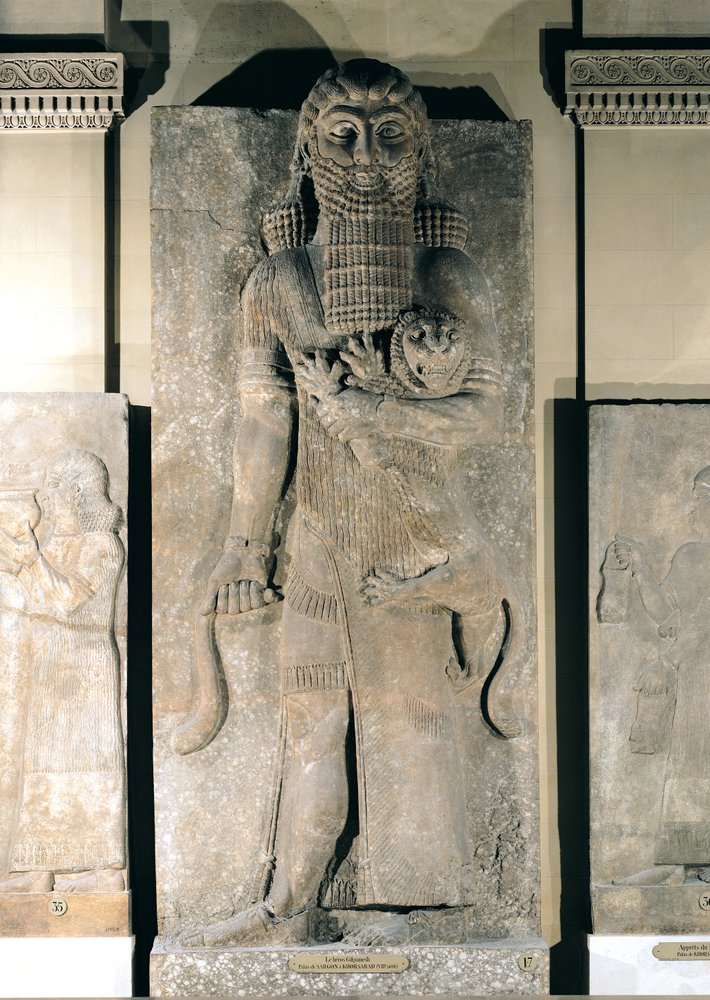 The hero Gilgamesh holding a lion that he has captured, stone relief ...