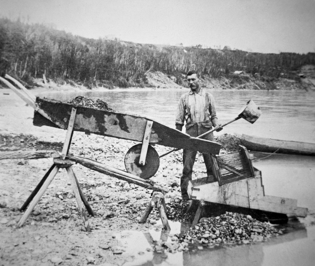 A prospector loading a 'rocker' or 'cradle' to wash gold from Klondike ...