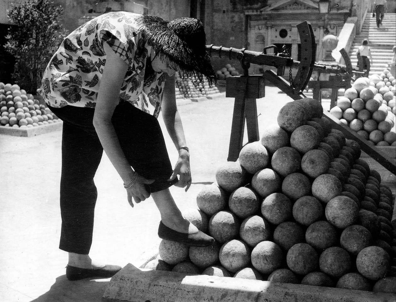 A woman adjusts the cuff of her pants as she rests her foot on a pile of cannonballs inside the ...
